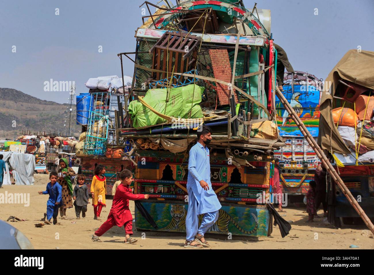 Afghan refugees children play next to trucks loaded with their family's ...