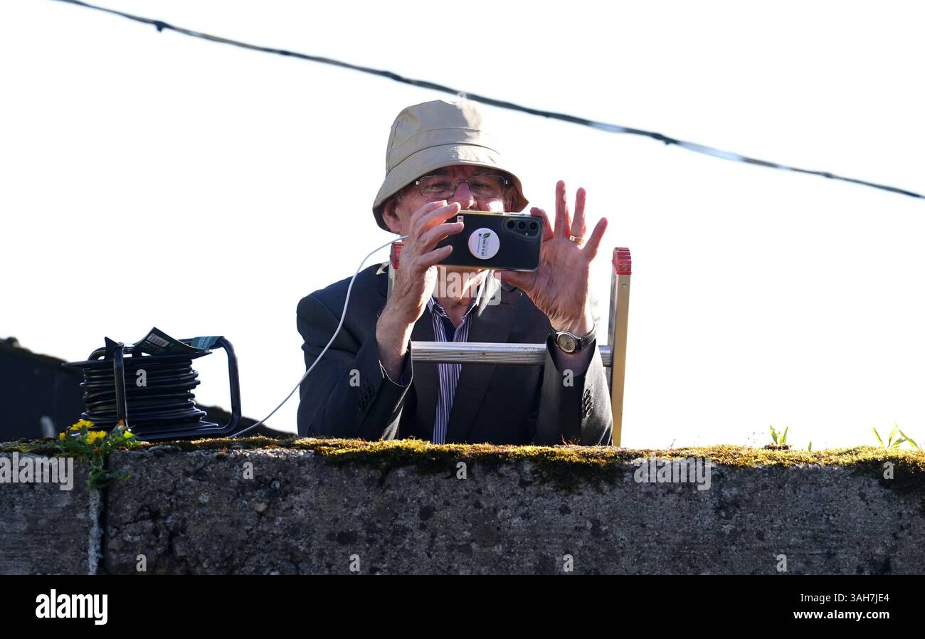 A local takes a photograph on a ladder during the 2025 Randox Aintree ...