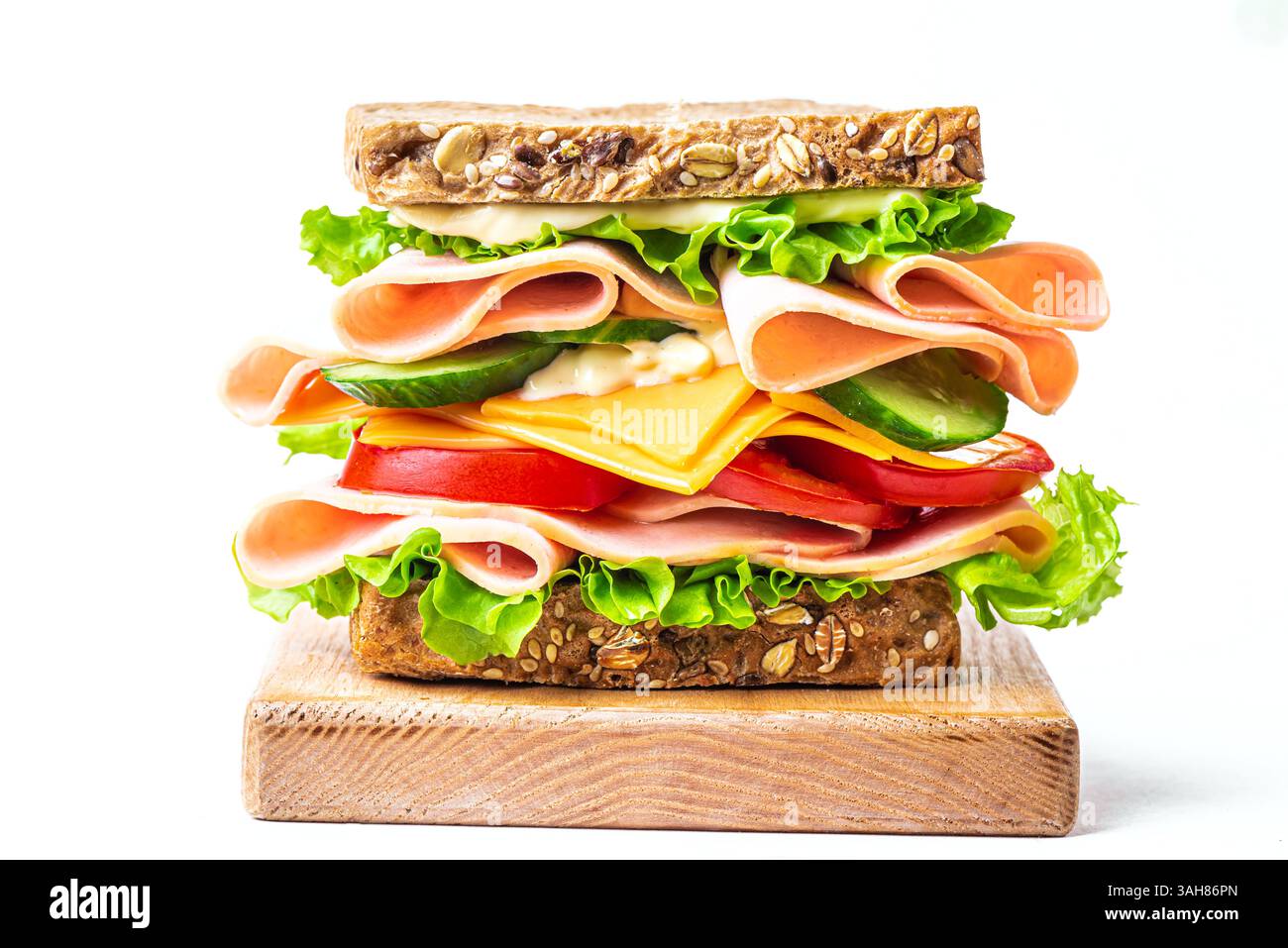 Big layered sandwich with ham, lettuce, cheddar cheese, tomato and ...
