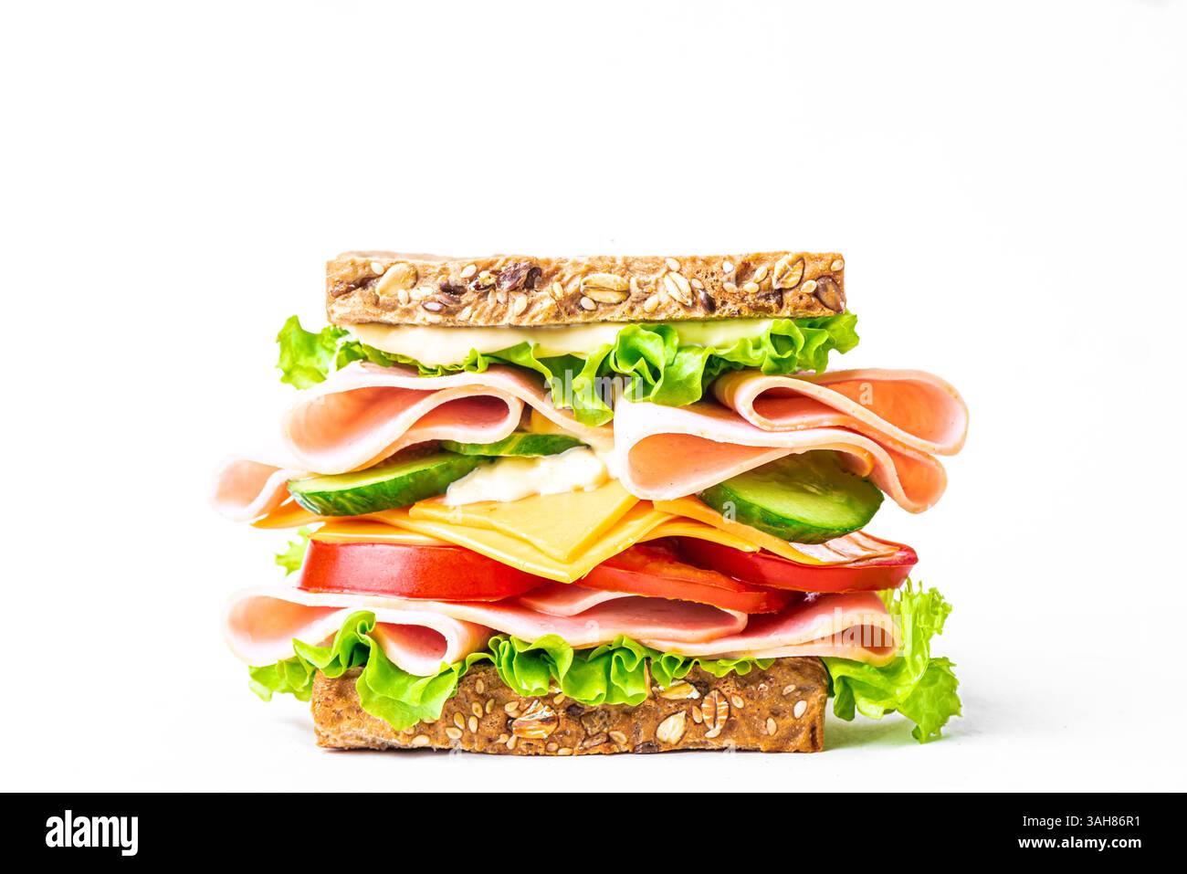 Big layered sandwich with ham, lettuce, cheddar cheese, tomato and ...