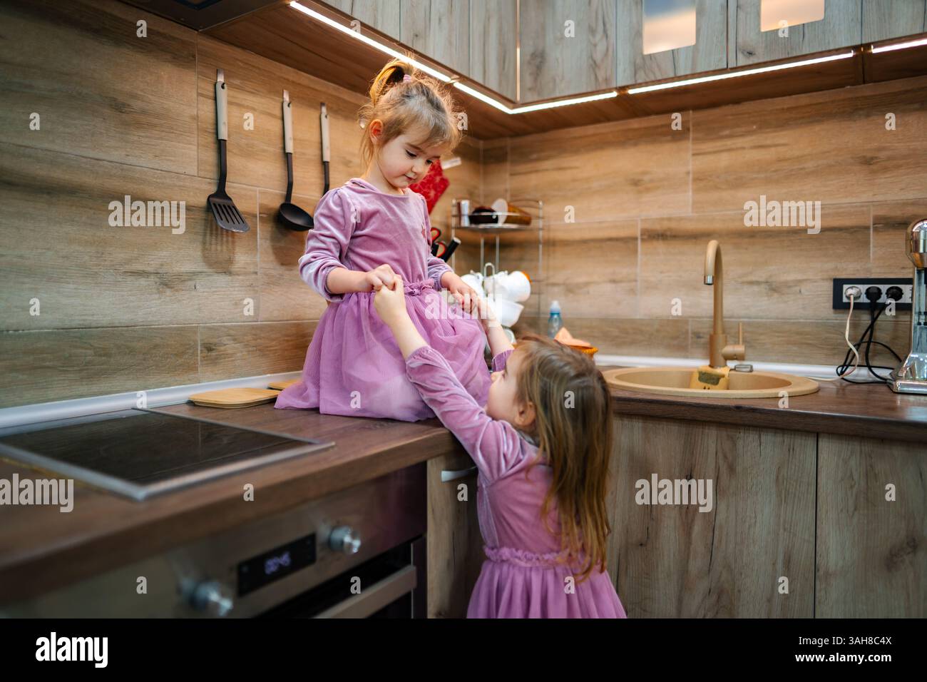 Sisters enjoying playful moments in a cozy kitchen while sharing a ...