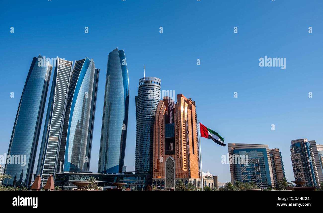 United Arab Emirates flag waving on blue sky, High rise buildings ...