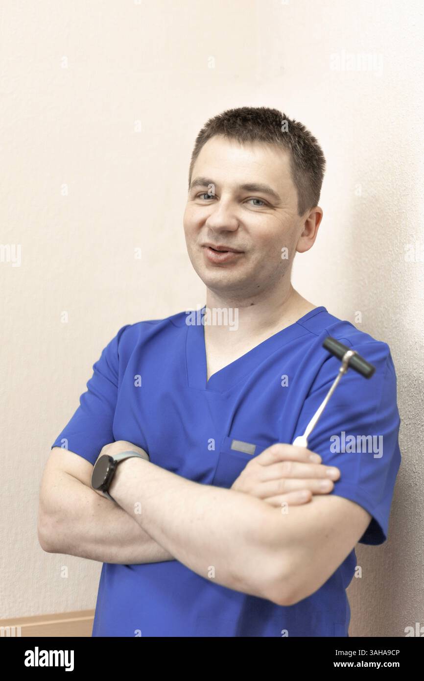 a male doctor stands against the wall and holds a reflex nerve tapping ...