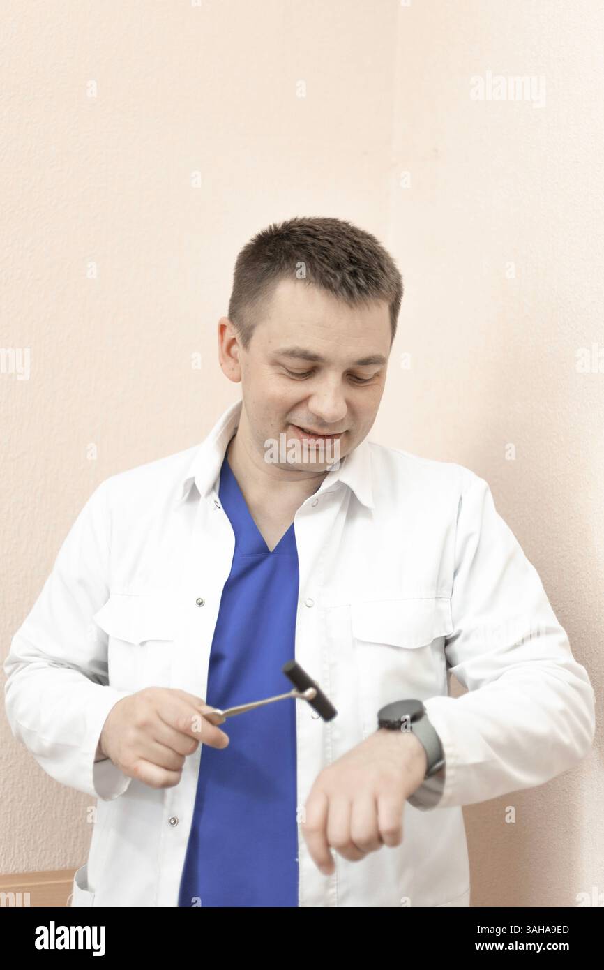 The doctor is holding a reflex nerve tapping instrument and looking at ...