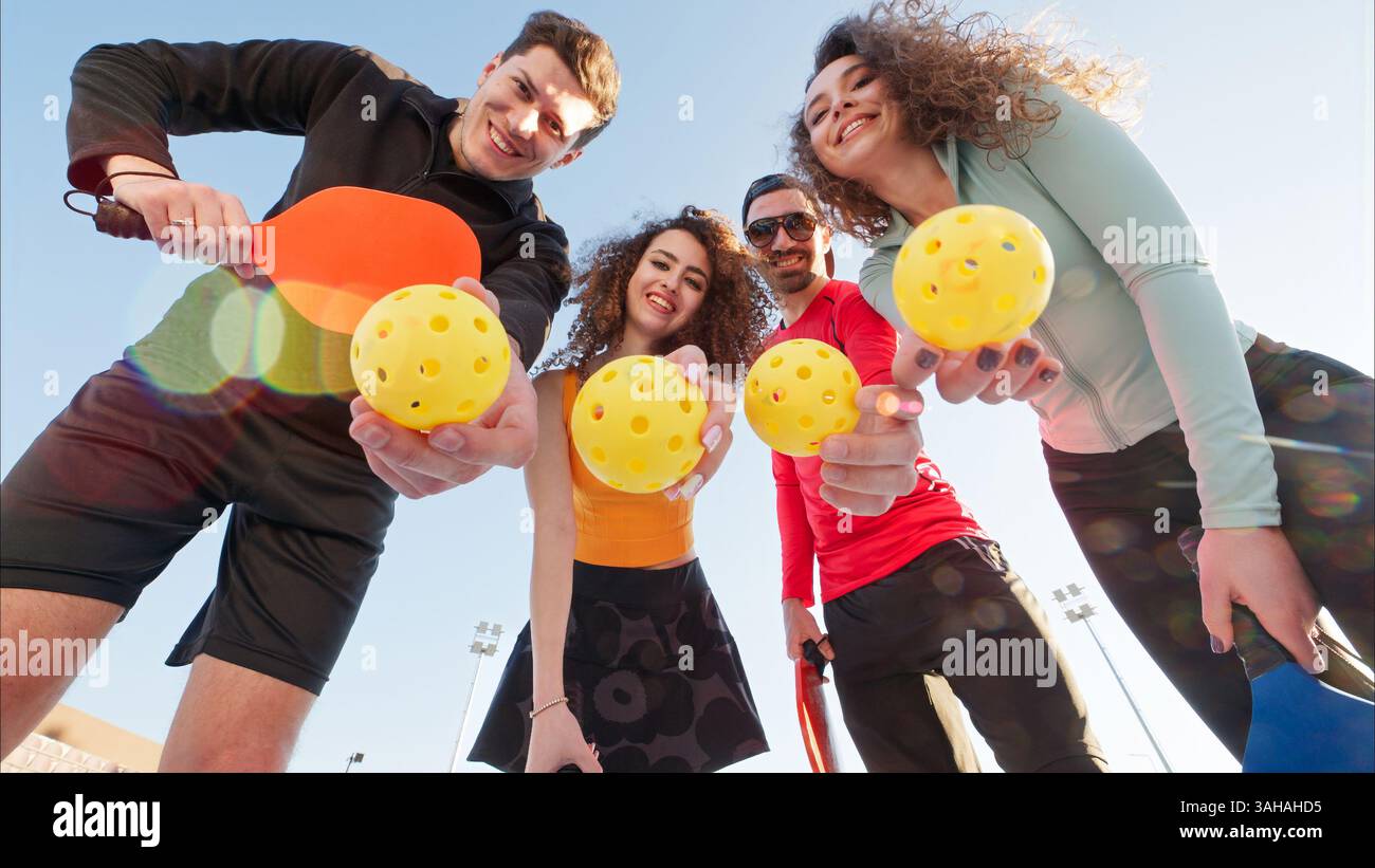 Group of smiling and happy friends holding pickleball ball and paddle ...