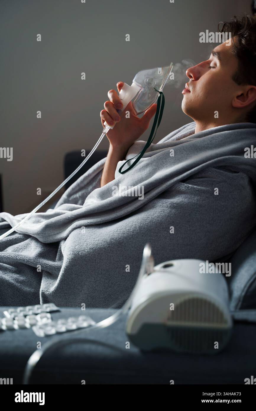 Using compressor nebulizer for disease treatment at home. Man inhaling ...