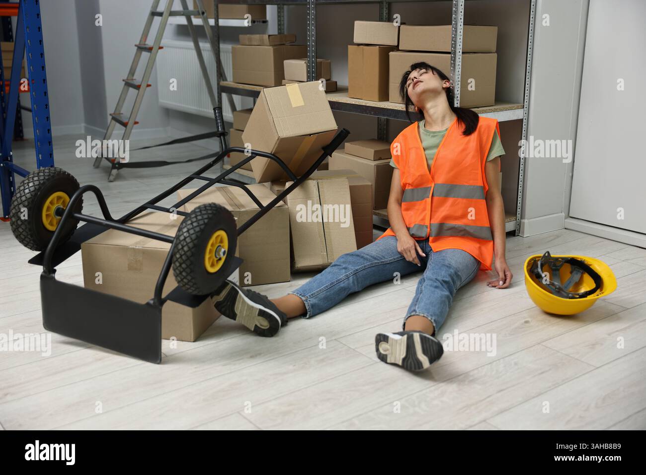 Accident at work. Unconscious woman and overturned hand truck on floor ...