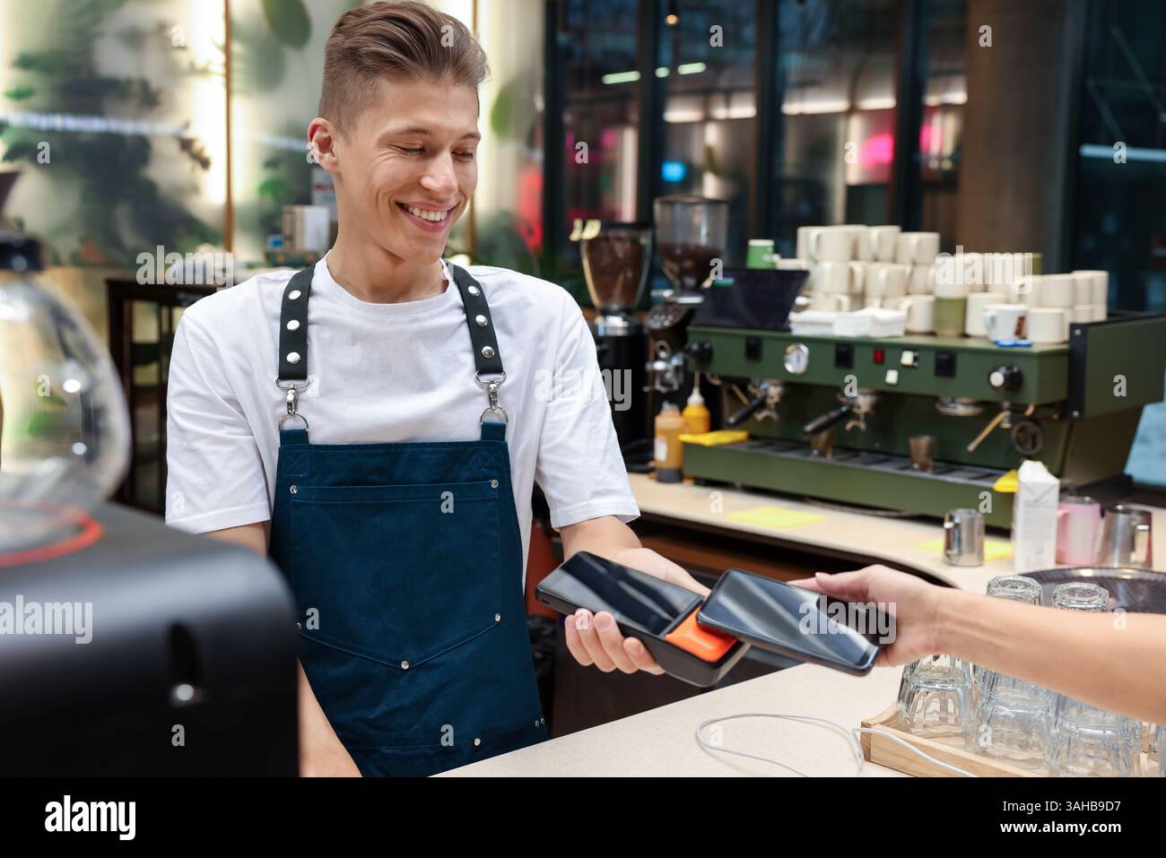 Cafe worker taking payment from client via terminal indoors Stock Photo ...