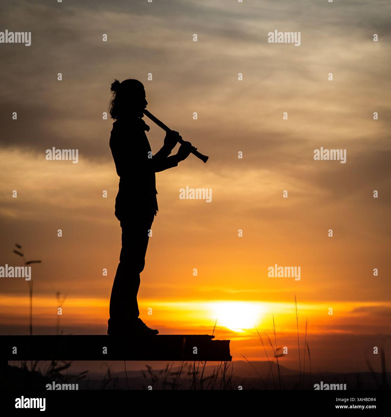 the silhouette of a male piper playing a flute against a setting sun on ...