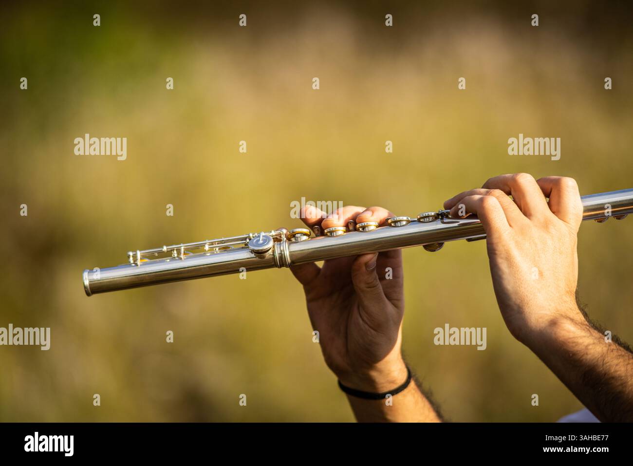 a metal c flute being played, held by caucasian male hands, with a hard ...