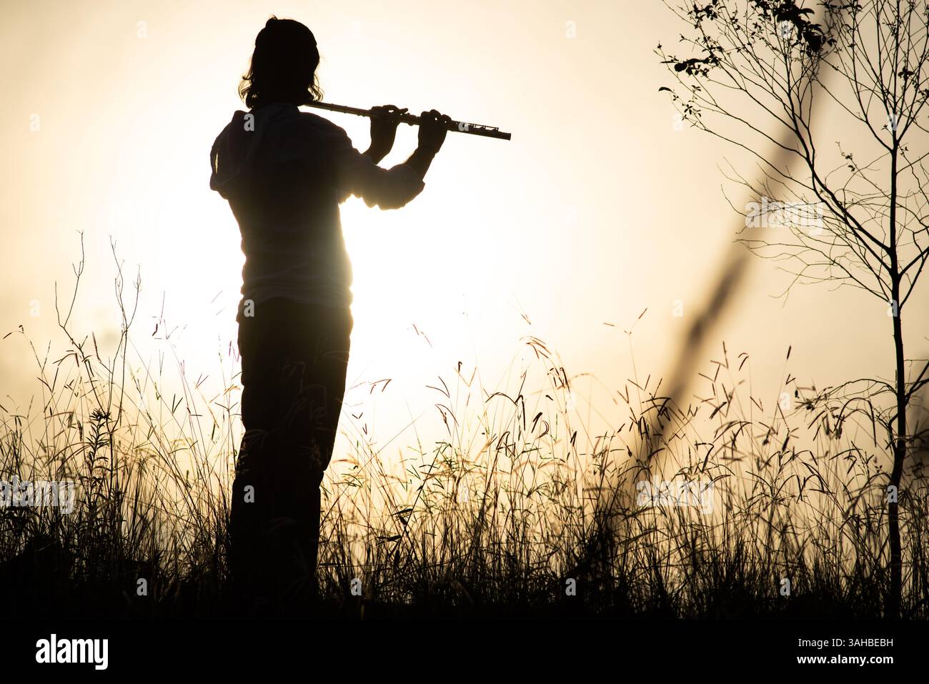 a piper playing a c flute against a hard sun in the background amidst a ...