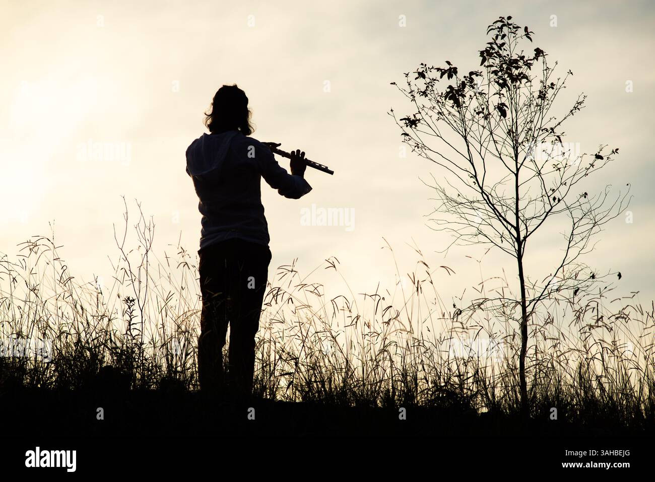 a piper playing a c flute against a hard sun in the background amidst a ...