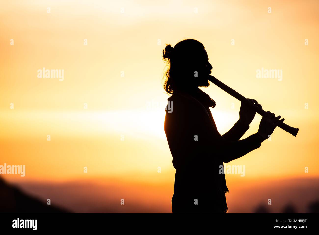 the silhouette of a male piper playing a flute against a setting sun on ...
