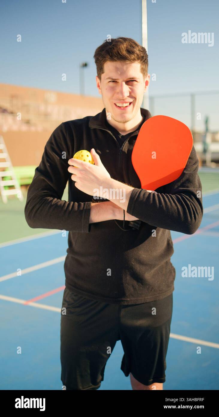 Portrait of a young, happy and smiling man holding pickleball paddle ...
