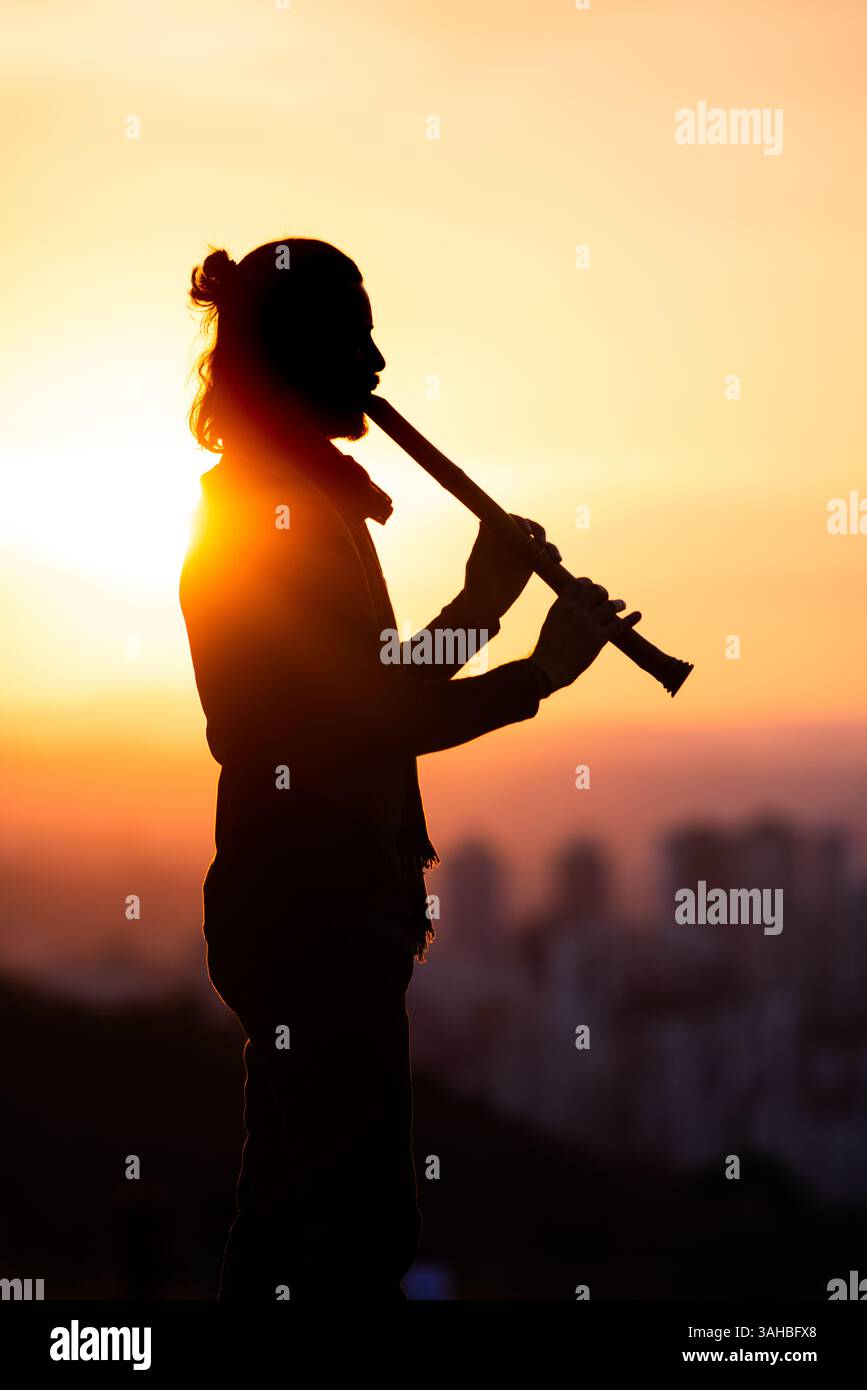 the silhouette of a male piper playing a flute against a setting sun on ...