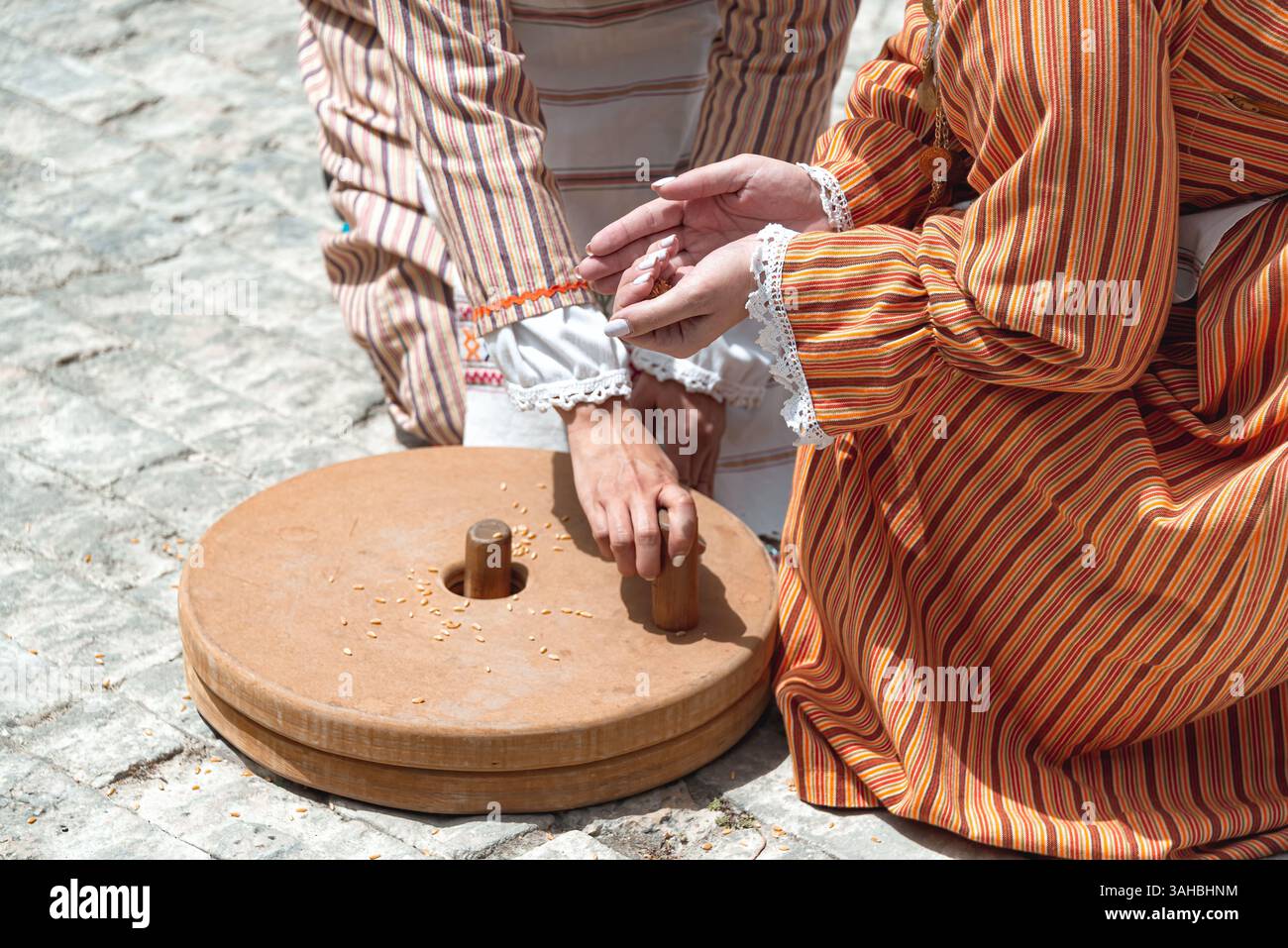 Traditional-dressed Cypriot women grinding wheat manually, revealing ...