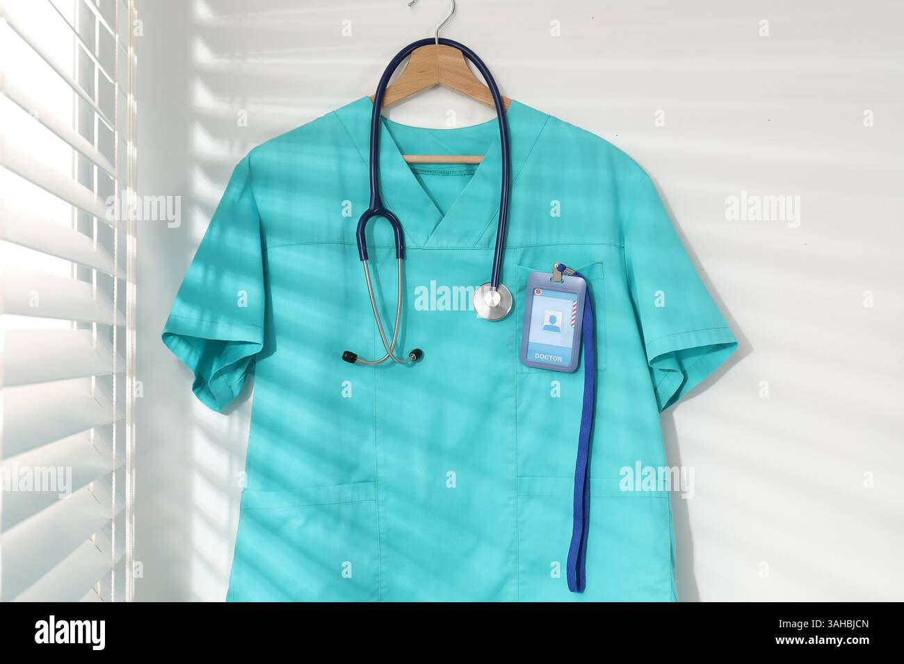 Medical worker uniform with stethoscope and badge on hanger against ...