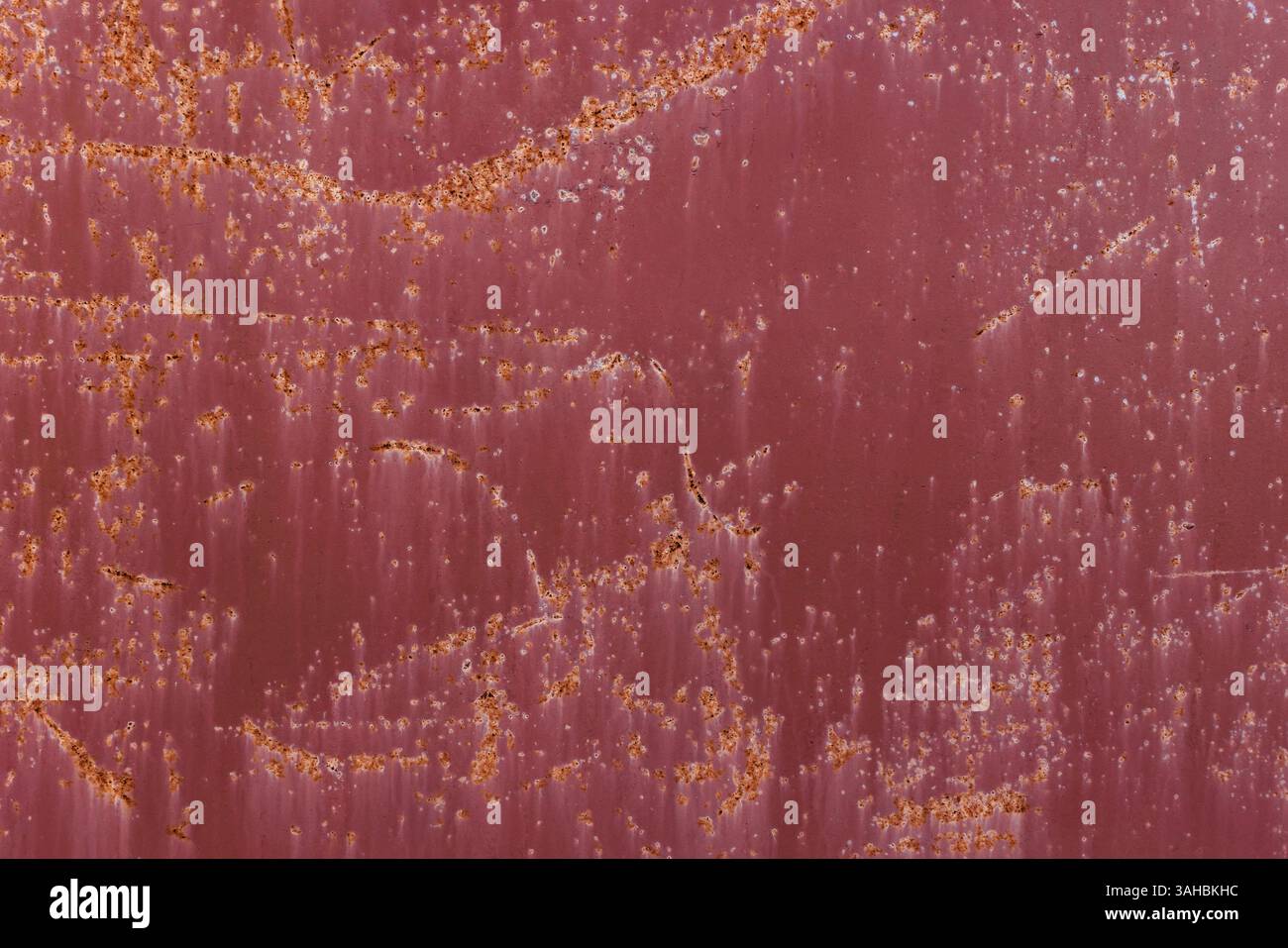 Red metal surface featuring extensive rust and corrosion, creating ...