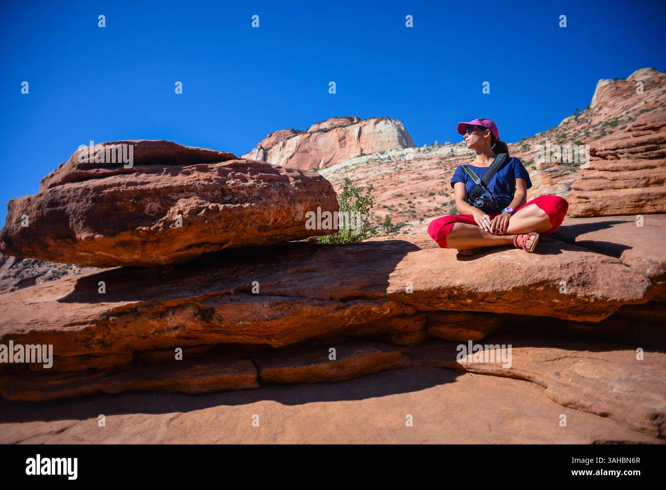 Young caucasian woman sitting with legs crossed in canyon overlook ...