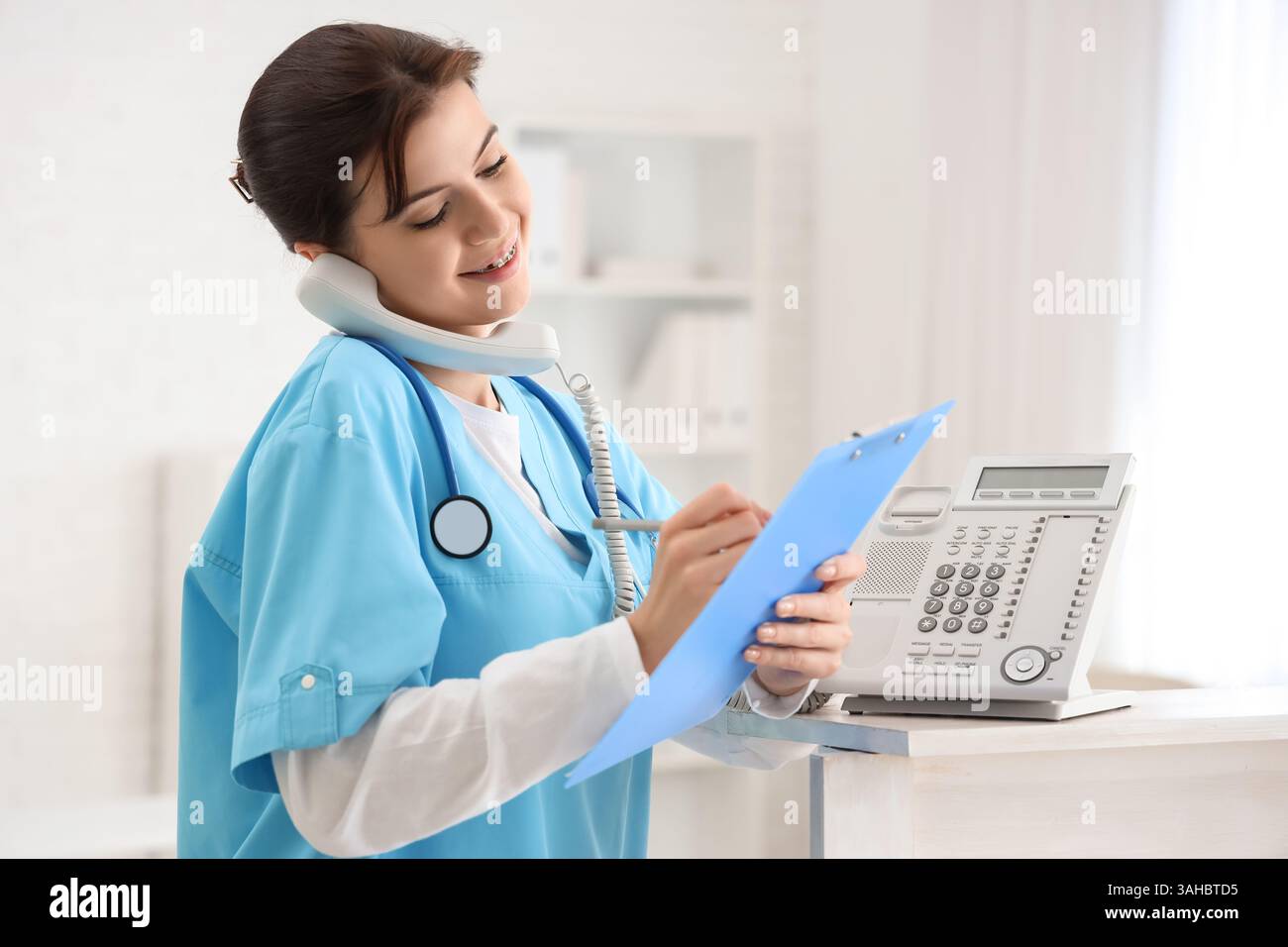 Female medical intern talking by telephone in clinic Stock Photo - Alamy