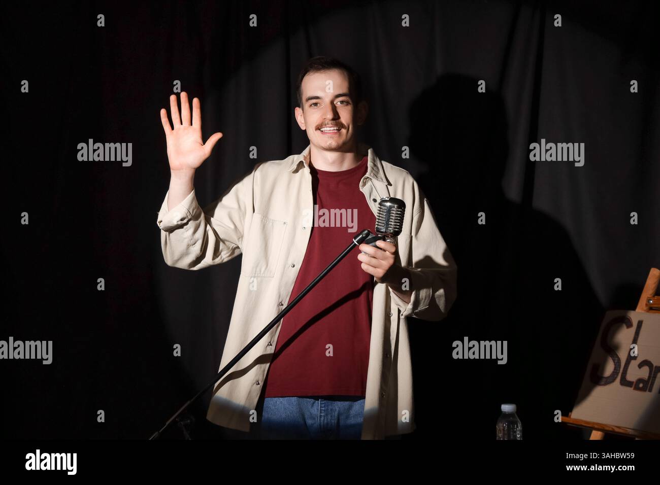 Standup comedian waving hand on stage Stock Photo - Alamy