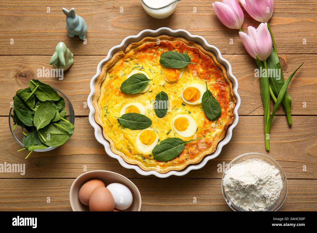 Delicious Easter egg tart with ingredients and tulip flowers on wooden ...