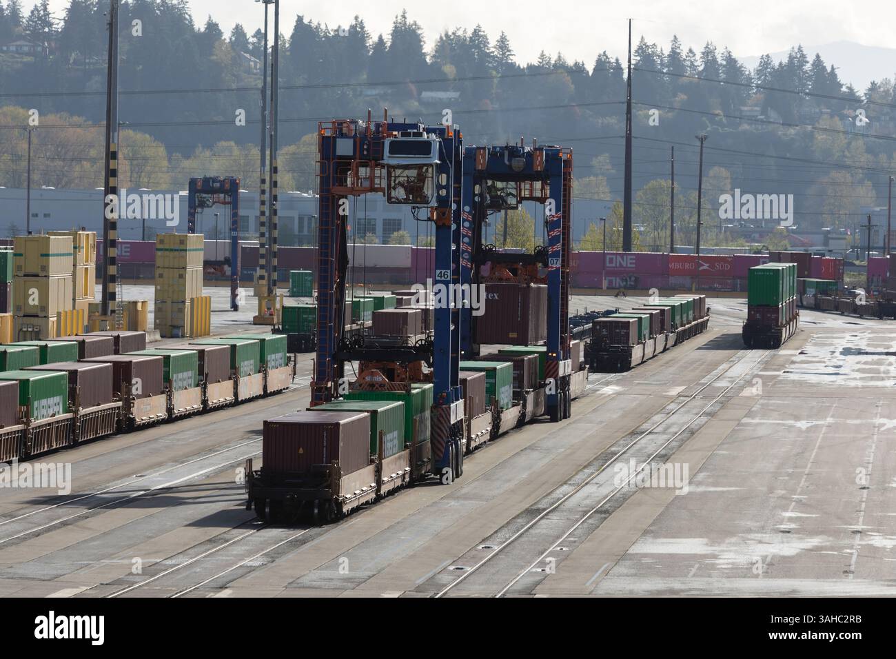 Straddle carriers rearrange shipping containers on rail cars at the ...