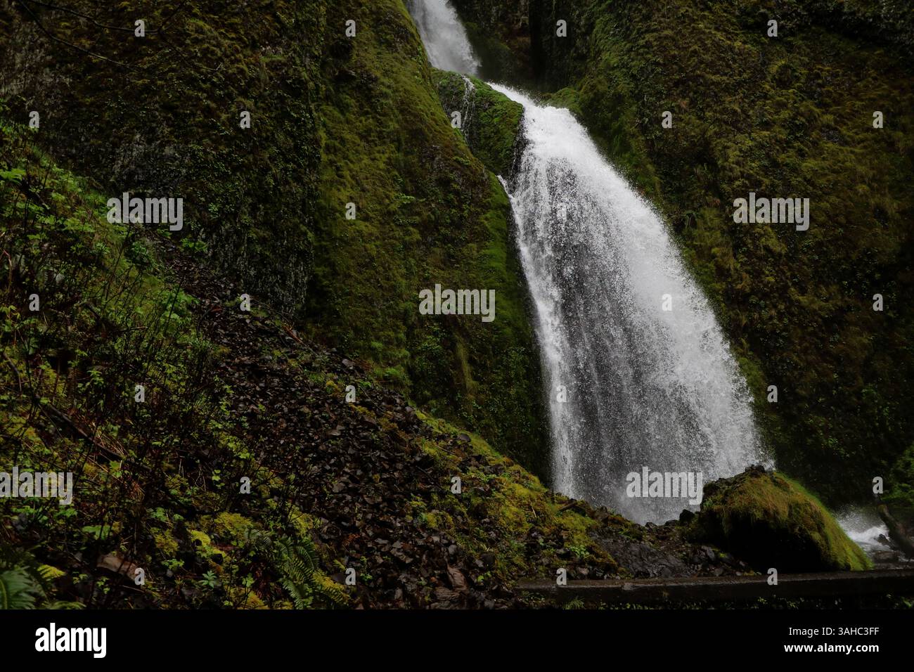 A waterfall surrounded by green moss behind a dark bridge. Found within ...