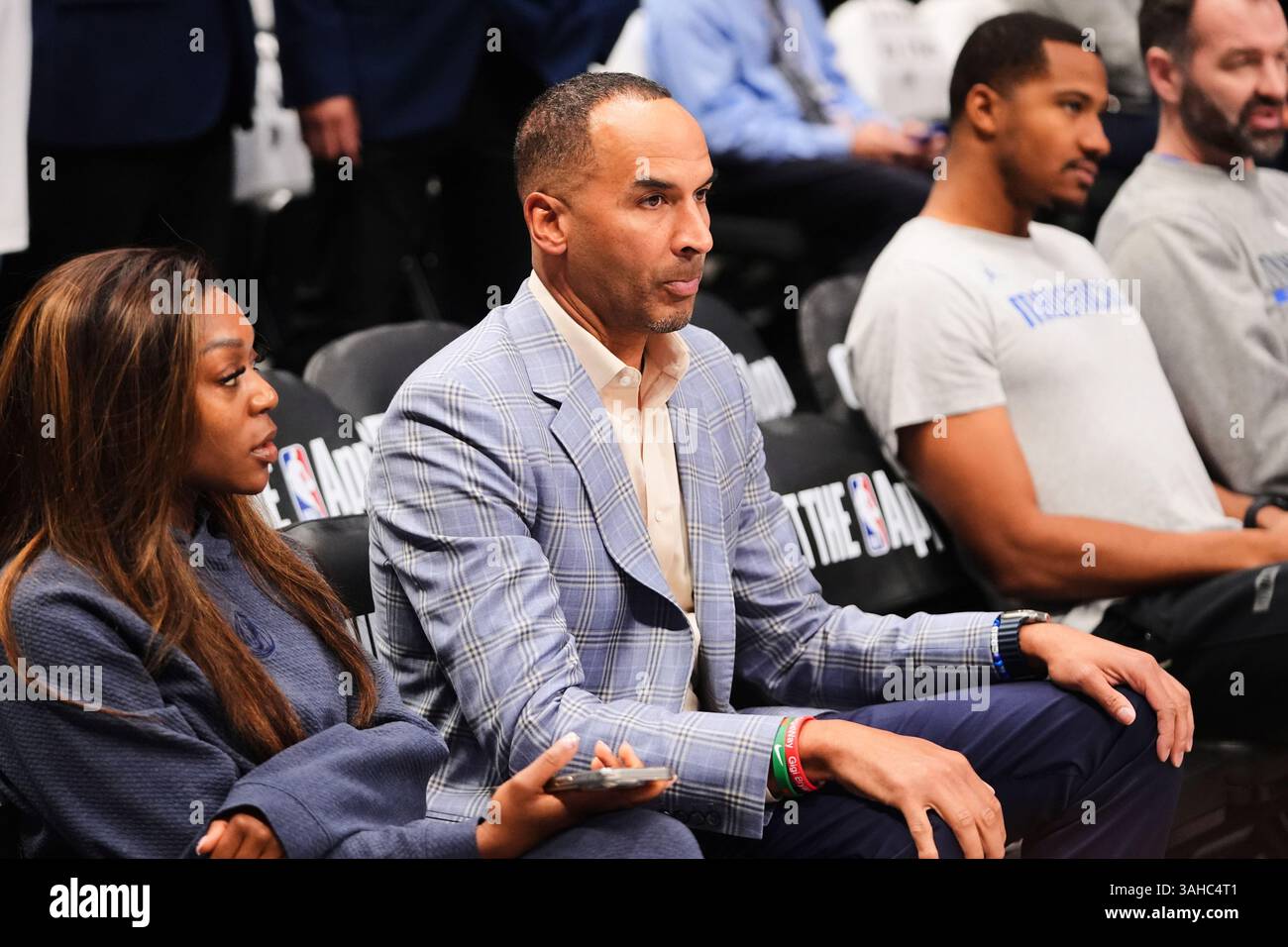 Nico Harrison, center, the Dallas Mavericks general manager watches warmups before an NBA ...