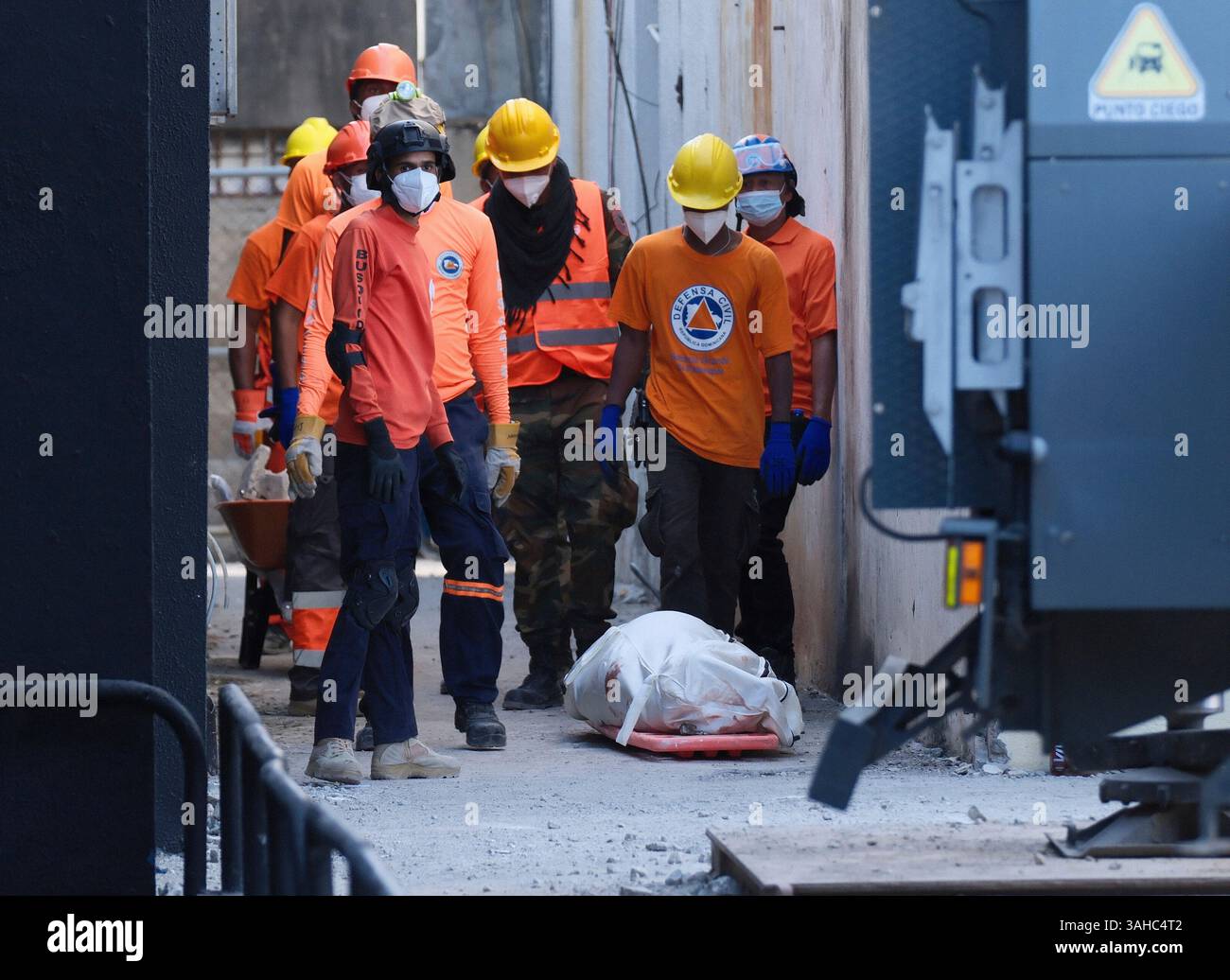 Rescue workers stand next to a recovered body of a victim who died when ...
