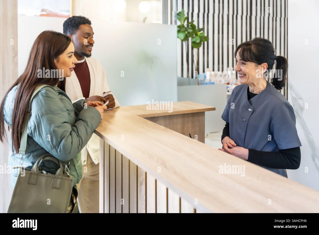 Interracial couple filling out paperwork at the reception desk of a ...