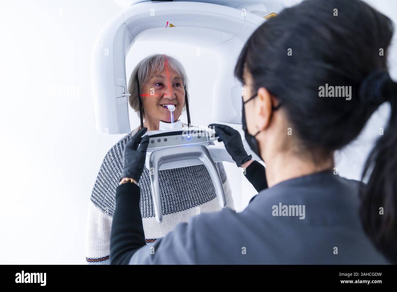Dentist positioning a 3d dental scanner on a senior woman patient ...