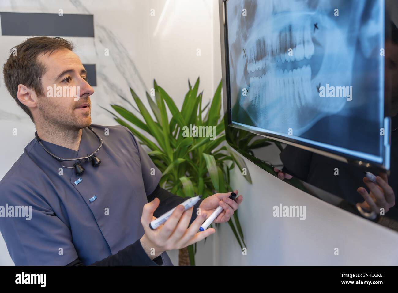 Dentist pointing at a dental x ray on a monitor, explaining diagnosis ...