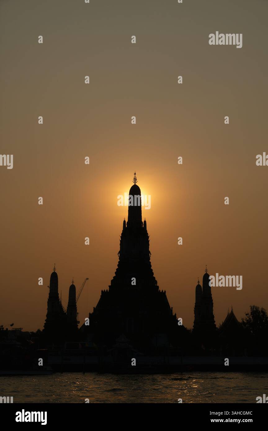 Golden sunset behind Wat Arun in Bangkok, casting a dramatic silhouette ...
