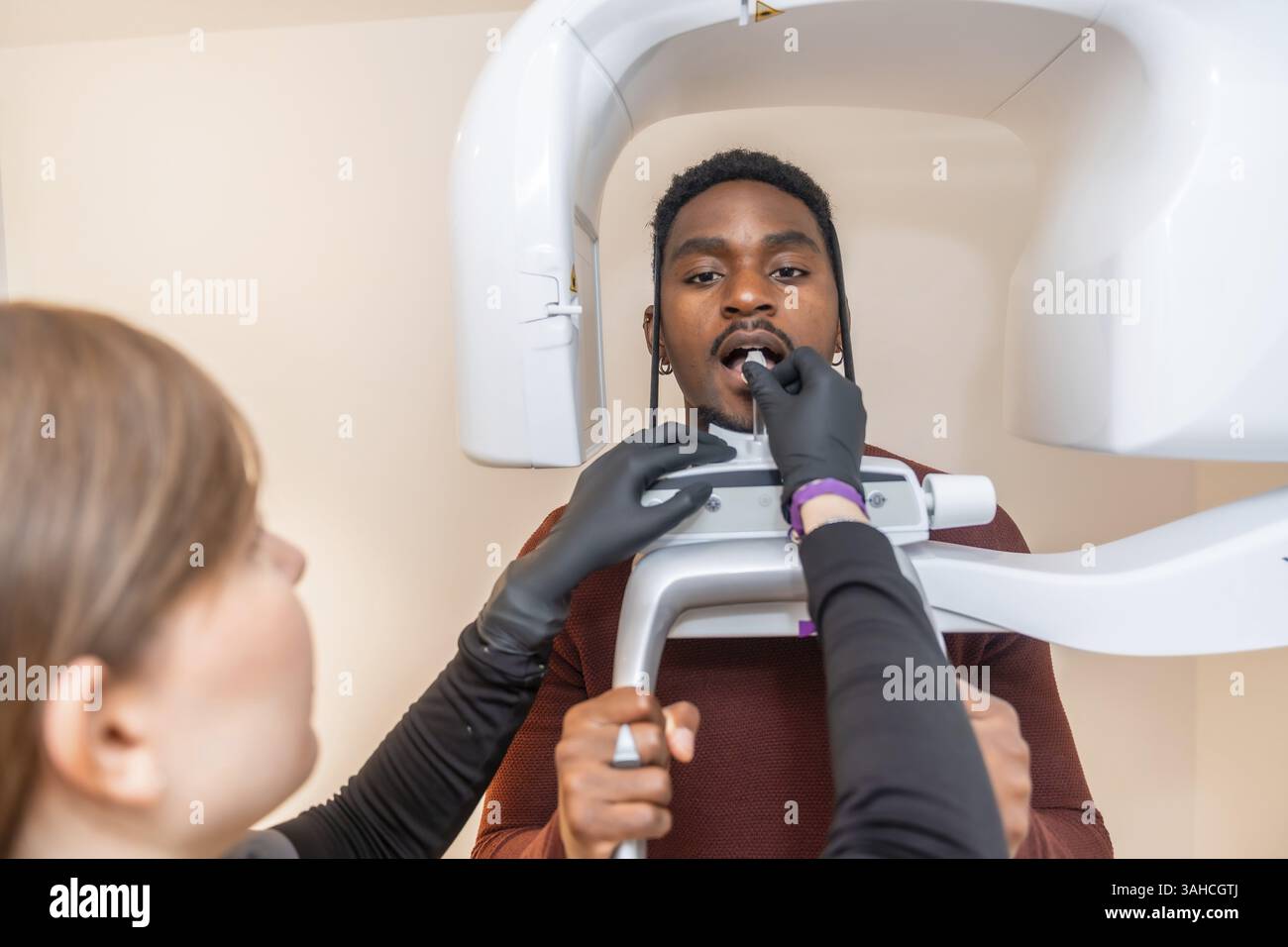 Dentist placing bite block in young man's mouth, preparing him for a ...