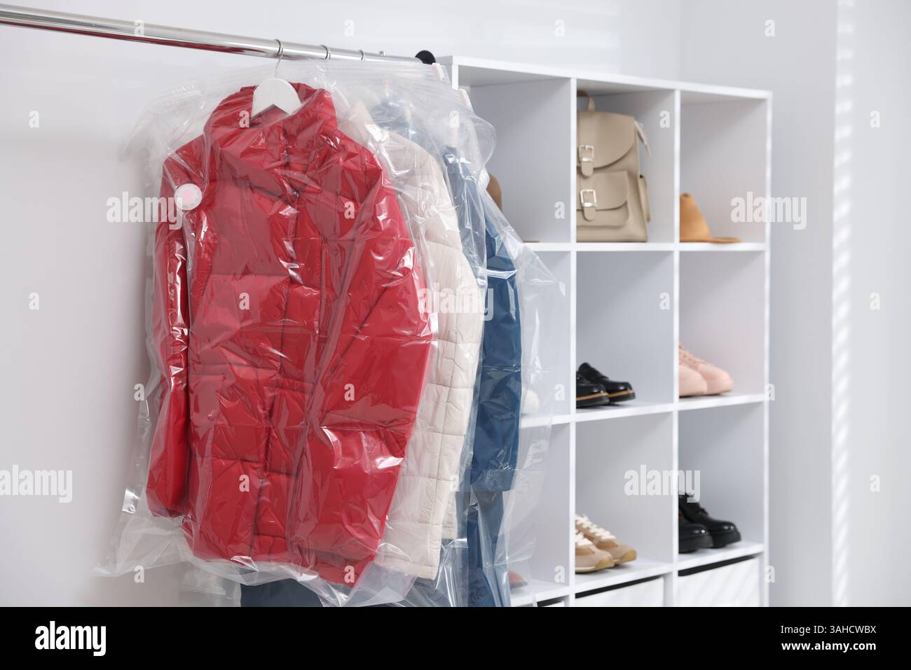 Compressed vacuum bags with clothes hanging on rack indoors Stock Photo ...
