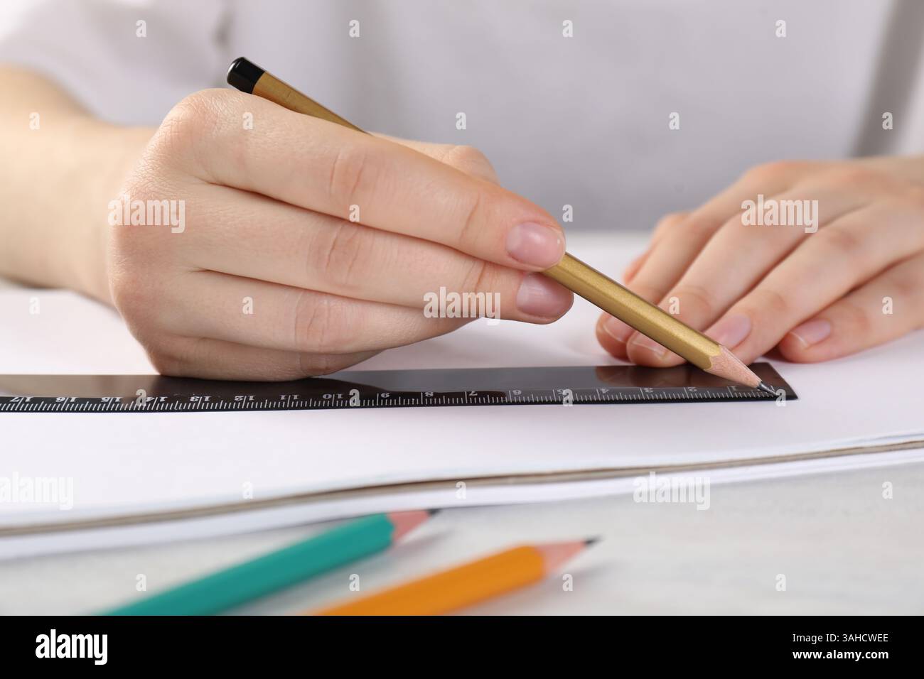 Woman drawing sketch with ruler and pencil on notebook at light table ...