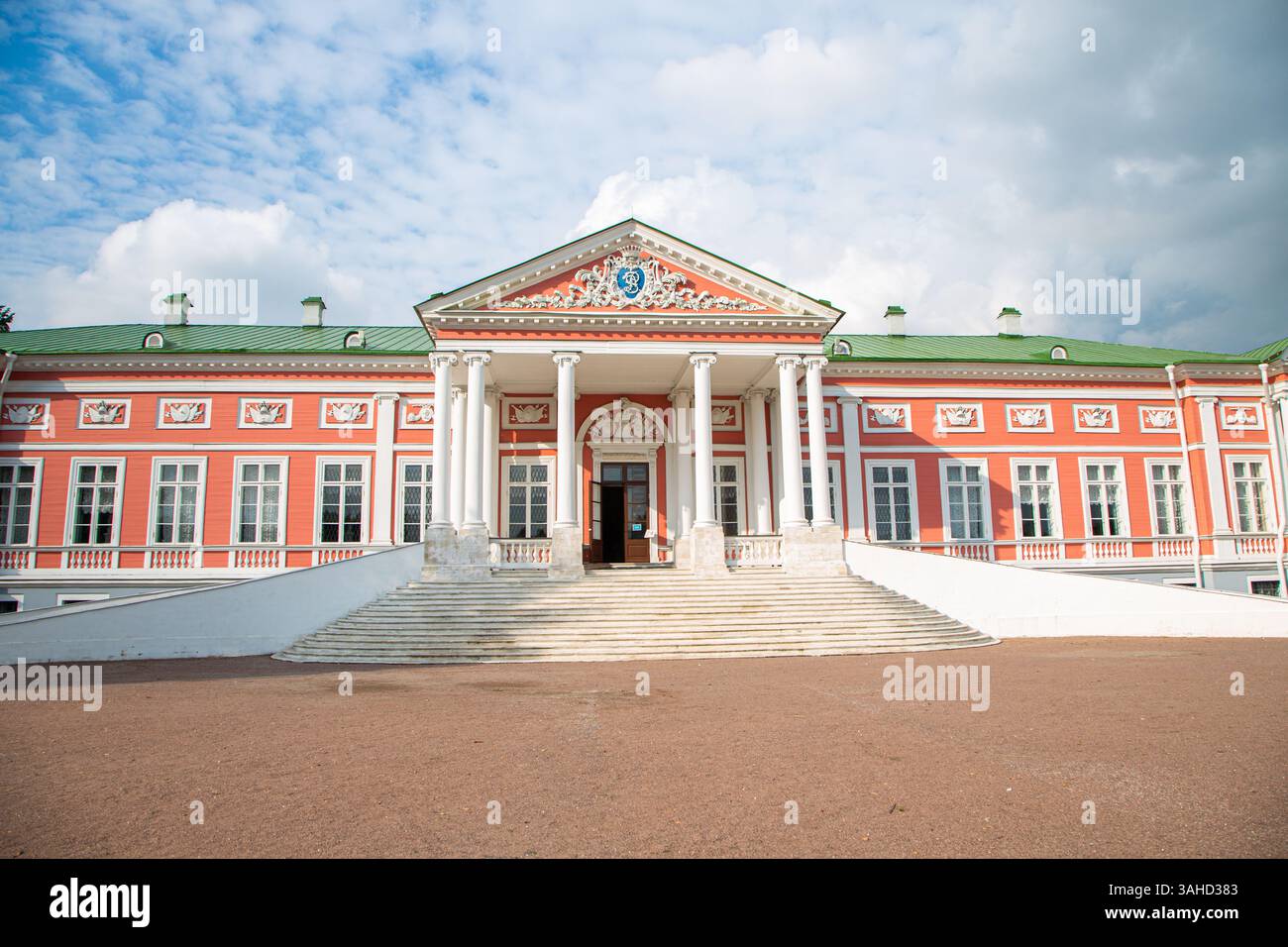 A large red building with white pillars and a green roof. The building ...