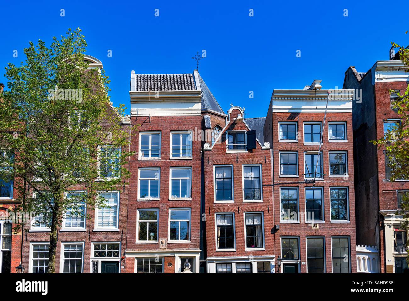Narrow tilting crooked houses along a canal in Amsterdam. Dancing ...