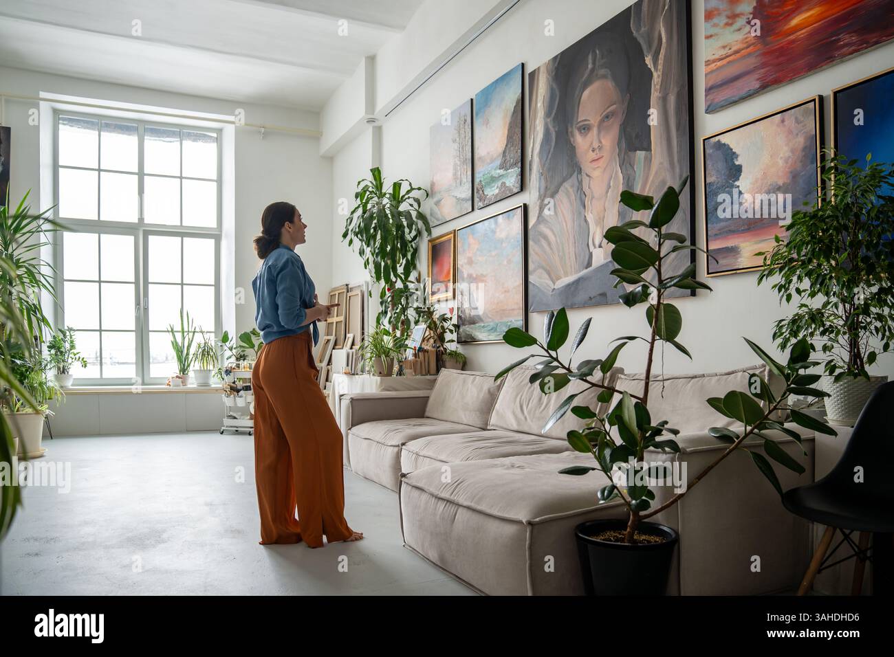 Thoughtful contemplative female artist examines portrait artwork among ...