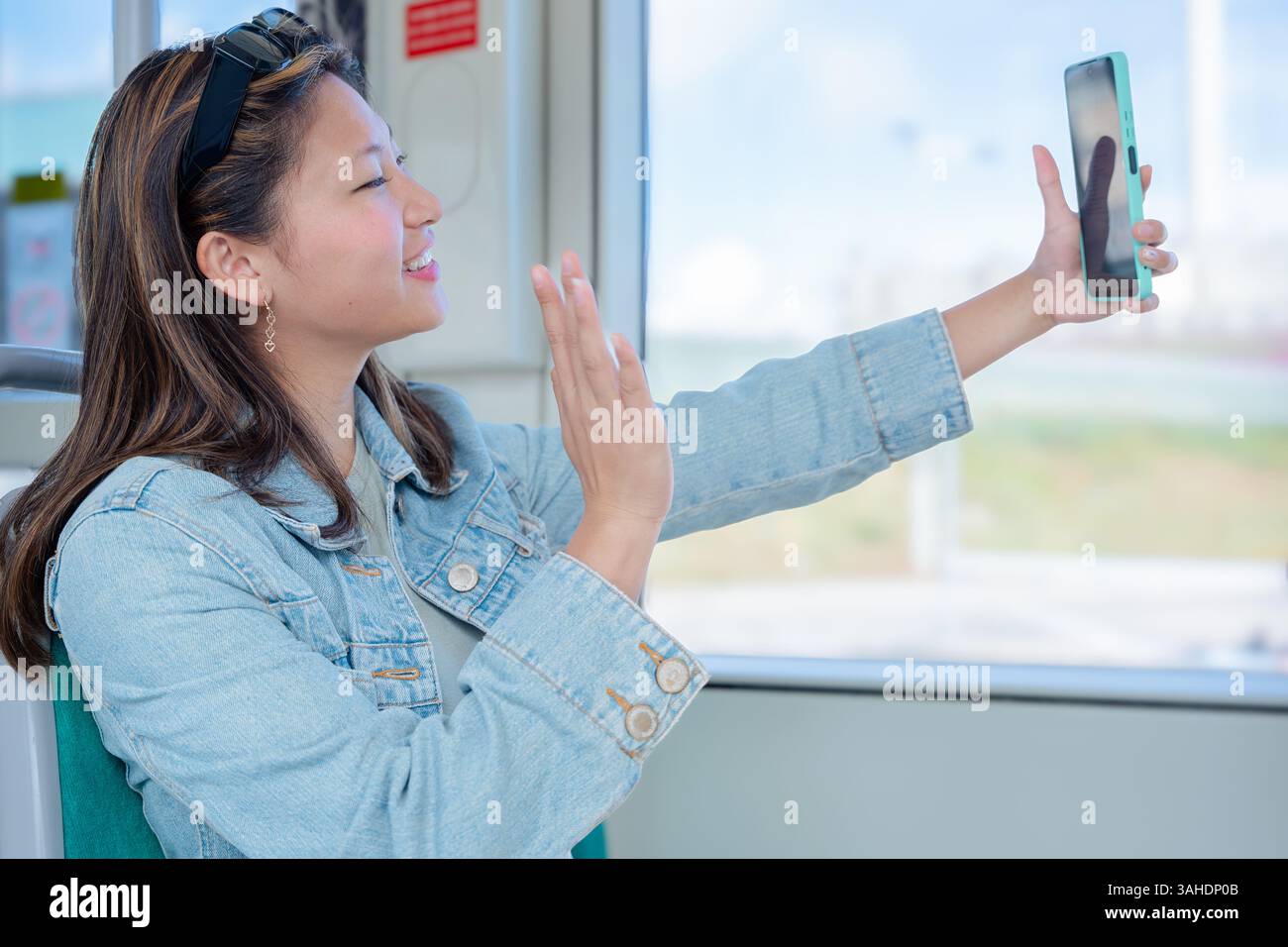Smiling chinese woman taking selfie on public transport while flashing ...