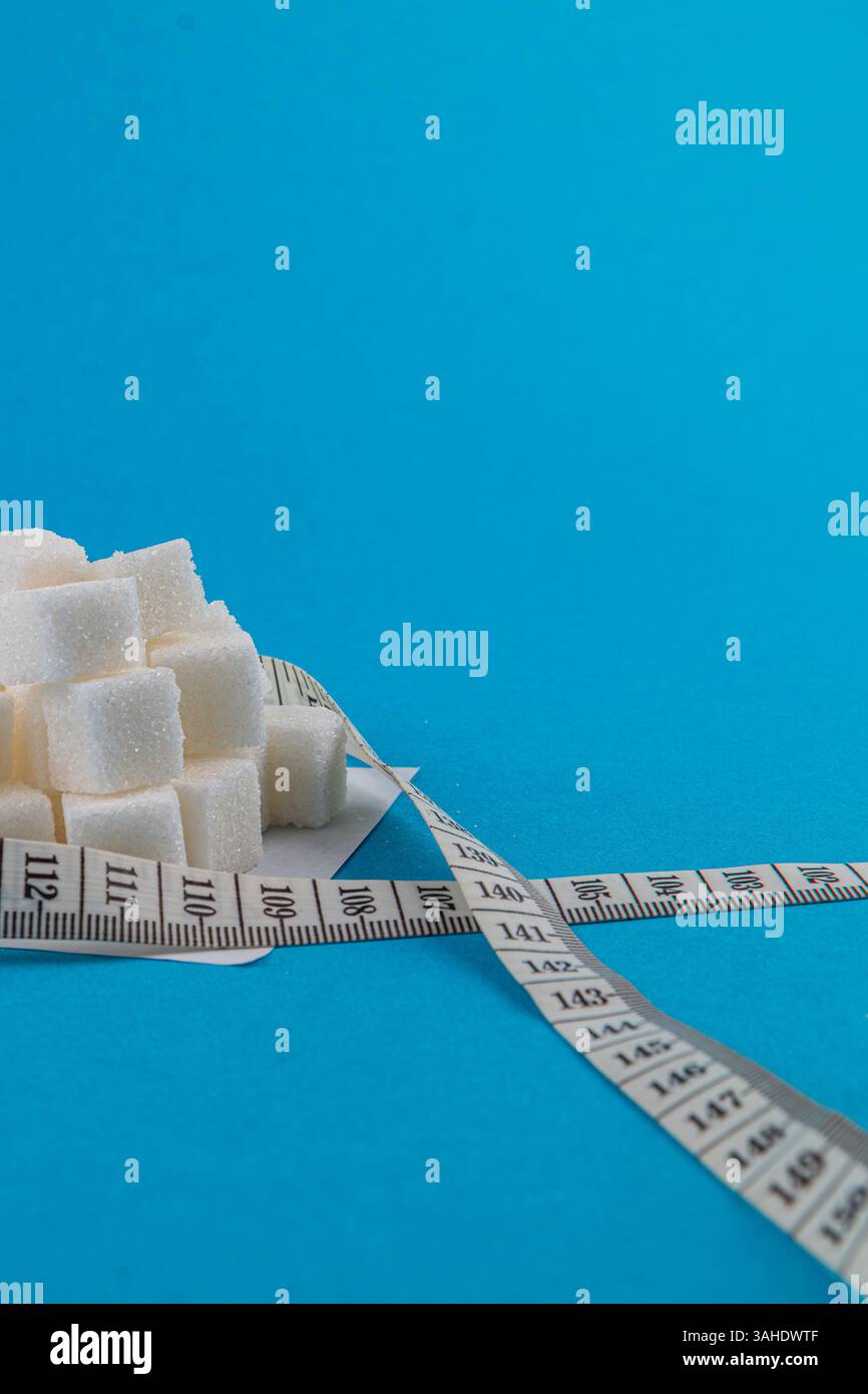 A collection of white sugar cubes is stacked on a vivid blue surface. A ...