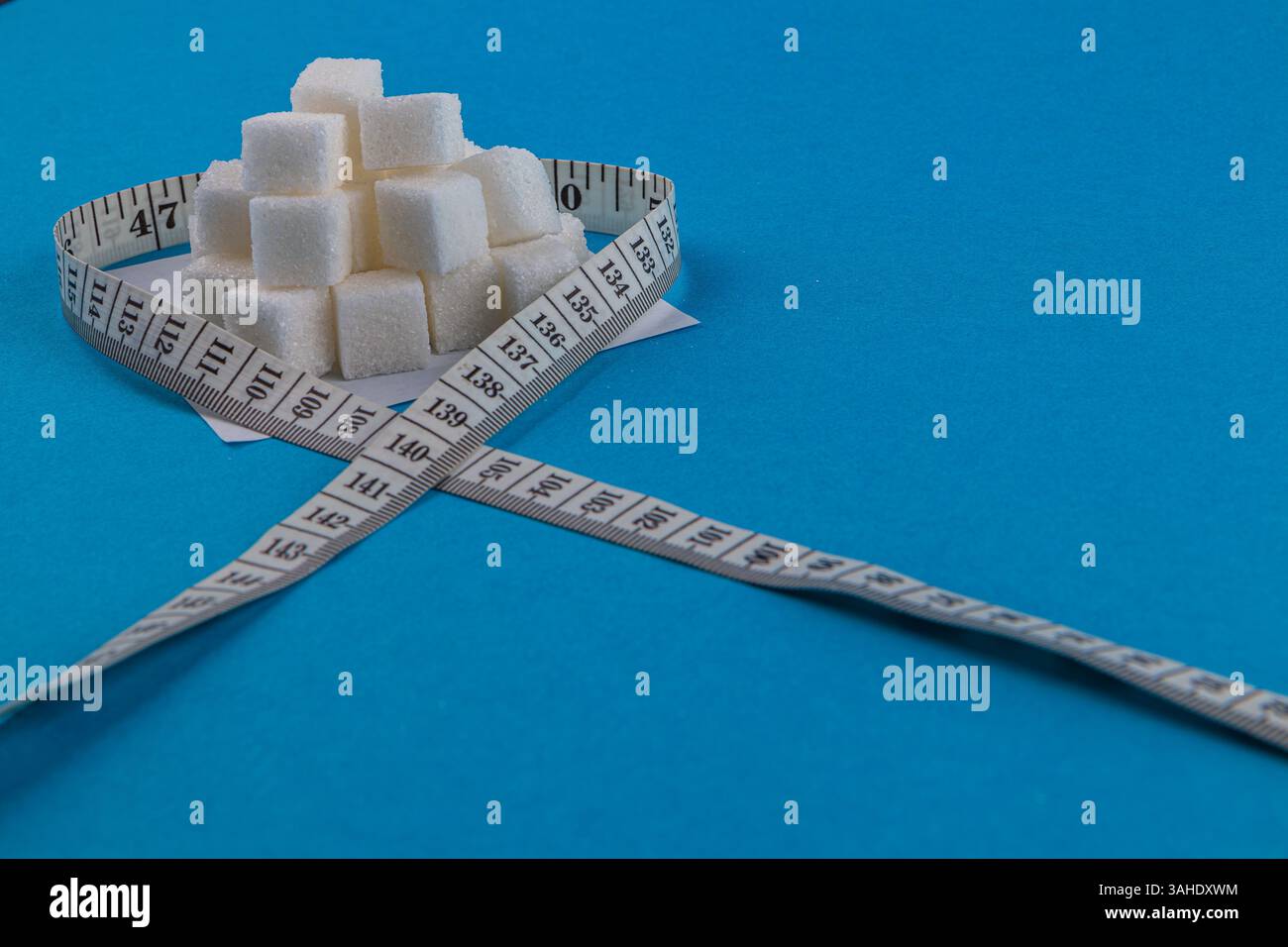 White sugar cubes are arranged in a pyramid shape on a bright blue ...