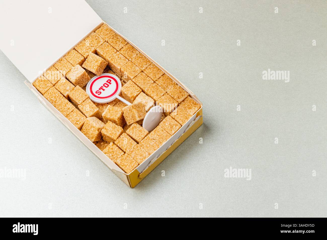 A box contains neatly arranged sugar cubes and features a small stop ...