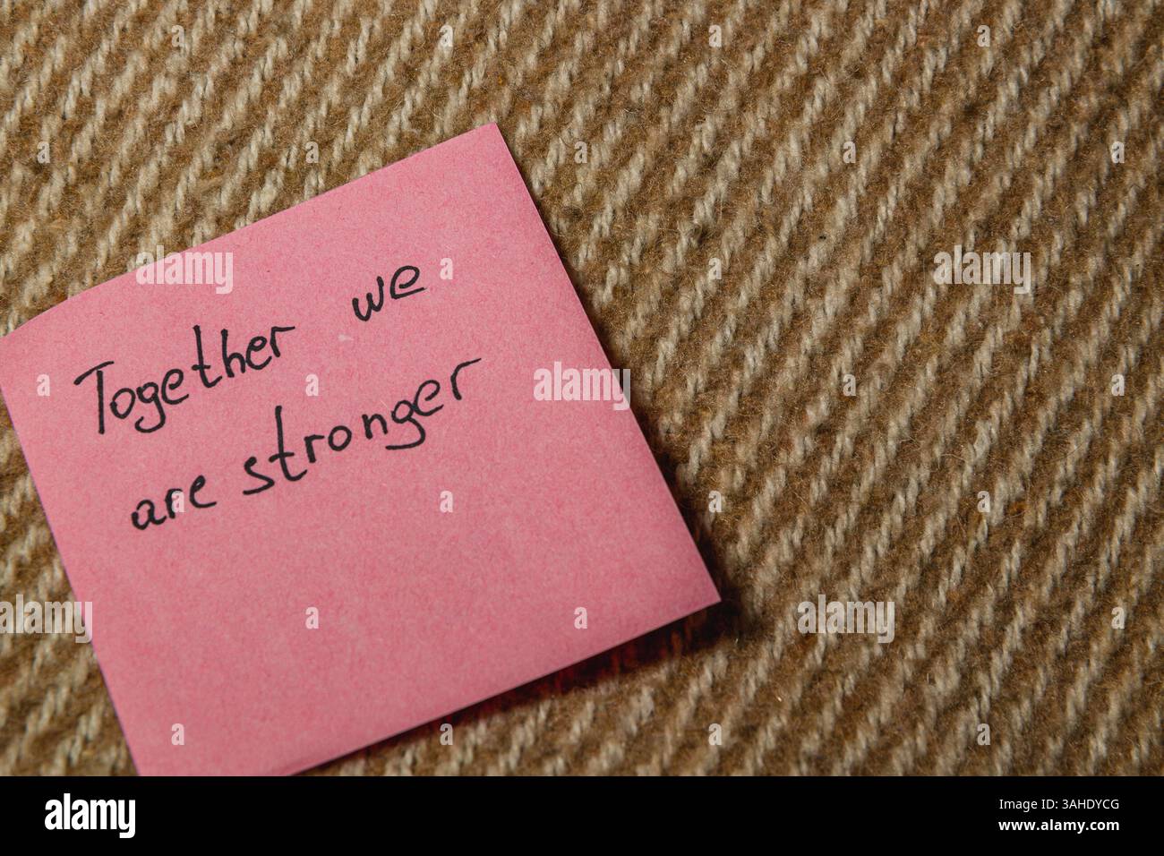 A pink sticky note with handwritten text reading Together we are ...