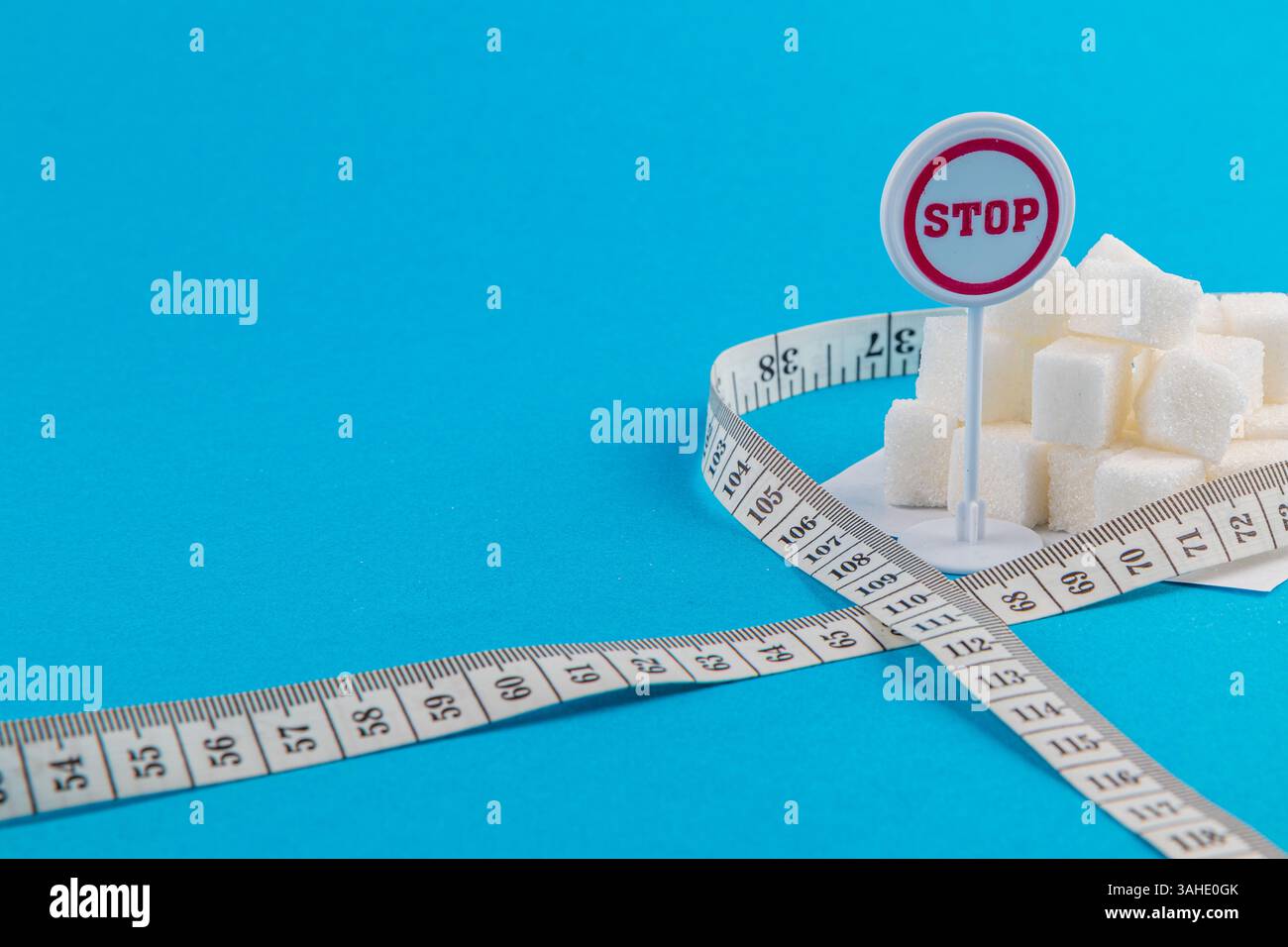 A stop sign stands next to sugar cubes with a measuring tape wound ...