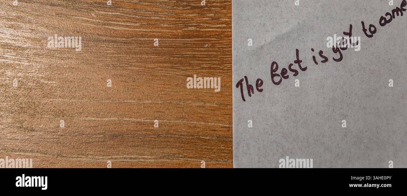 A handwritten note sits on a wooden table, conveying a positive message ...