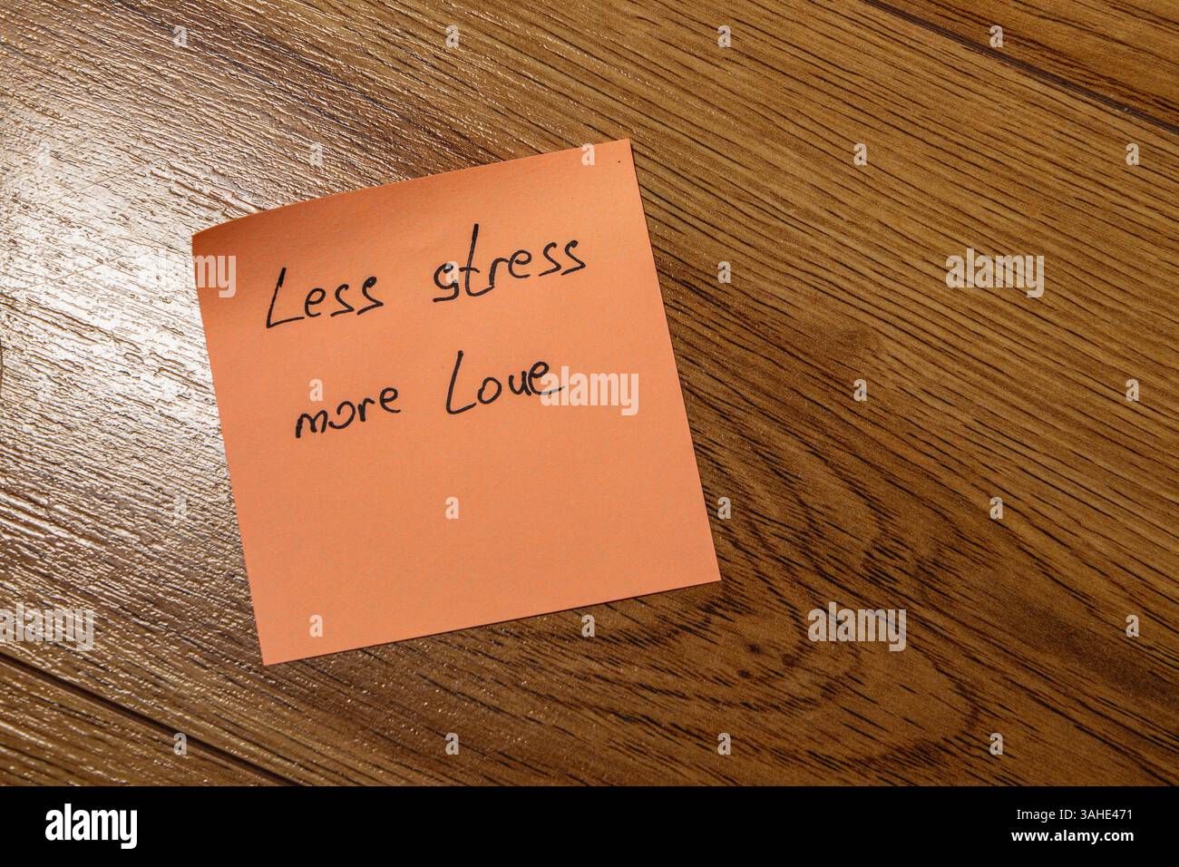 A small orange note placed on a wooden surface reads Less stress more ...