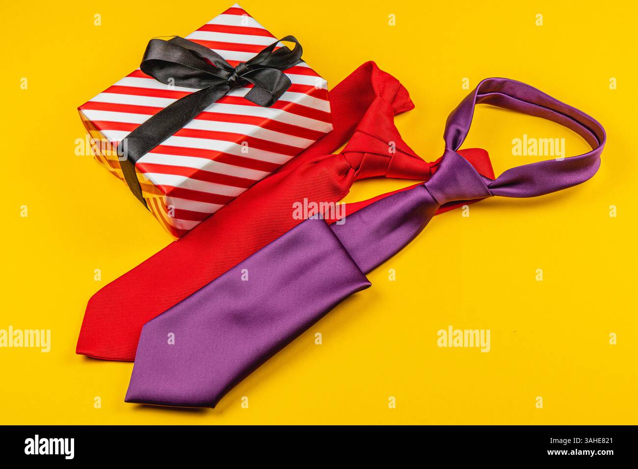 Two vibrant ties in red and purple lay beside a beautifully wrapped ...