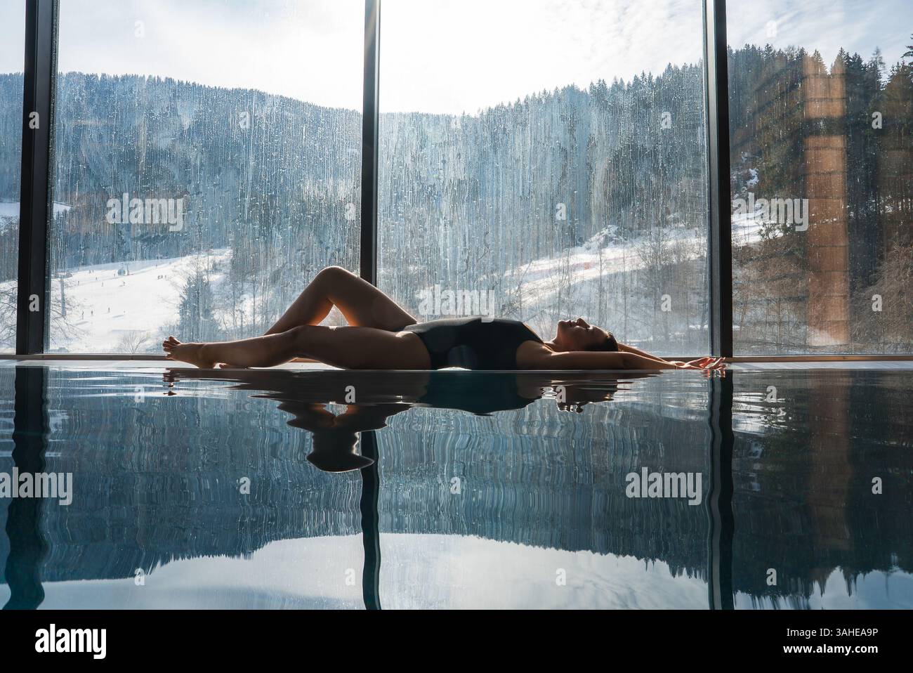 Woman Reclining by Indoor Infinity Pool with Alpine View Stock Photo ...